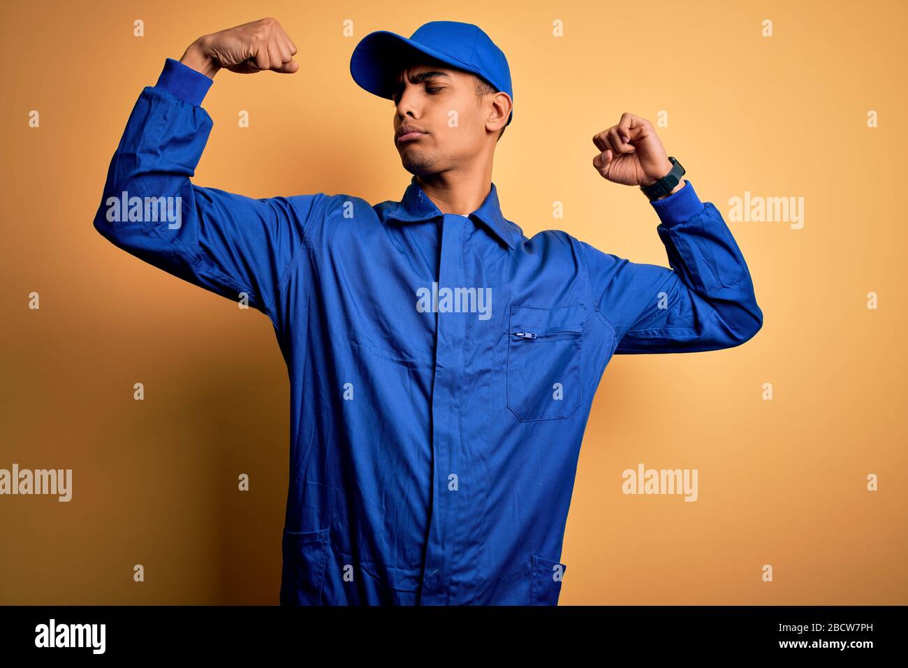 Young african american mechanic man wearing blue uniform and cap over ...