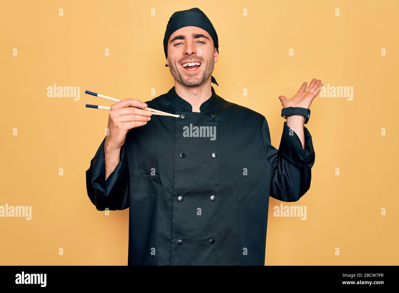 Young handsome cooker man with blue eyes wearing uniform and hat using ...
