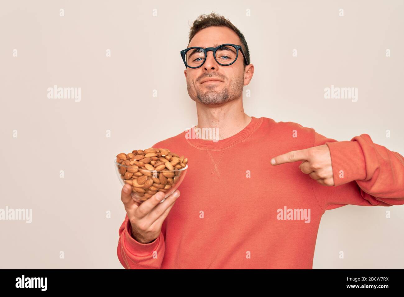 Handsome man with blue eyes holding bowl with healthy almonds snack ...