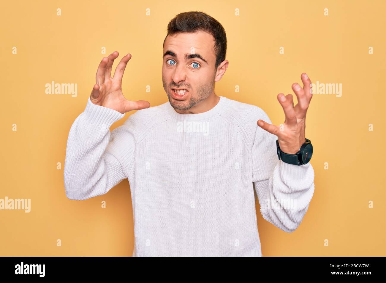 Young handsome man with blue eyes wearing casual sweater standing over ...