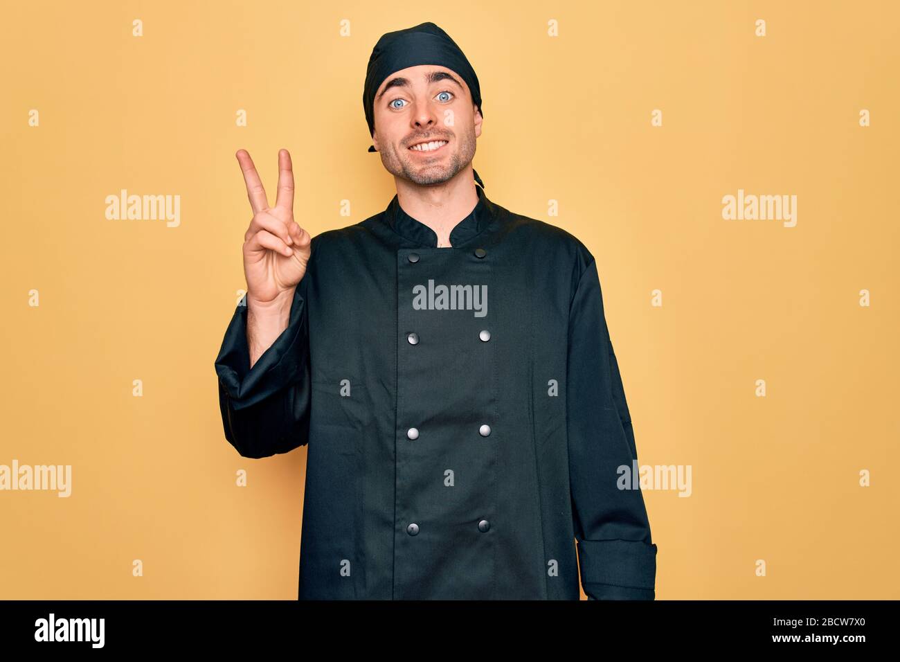 Young handsome cooker man with blue eyes wearing uniform and hat over ...