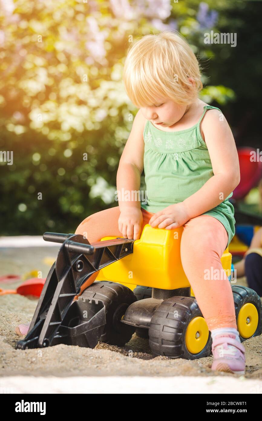 Child riding on a toy tractor on playground Stock Photo - Alamy