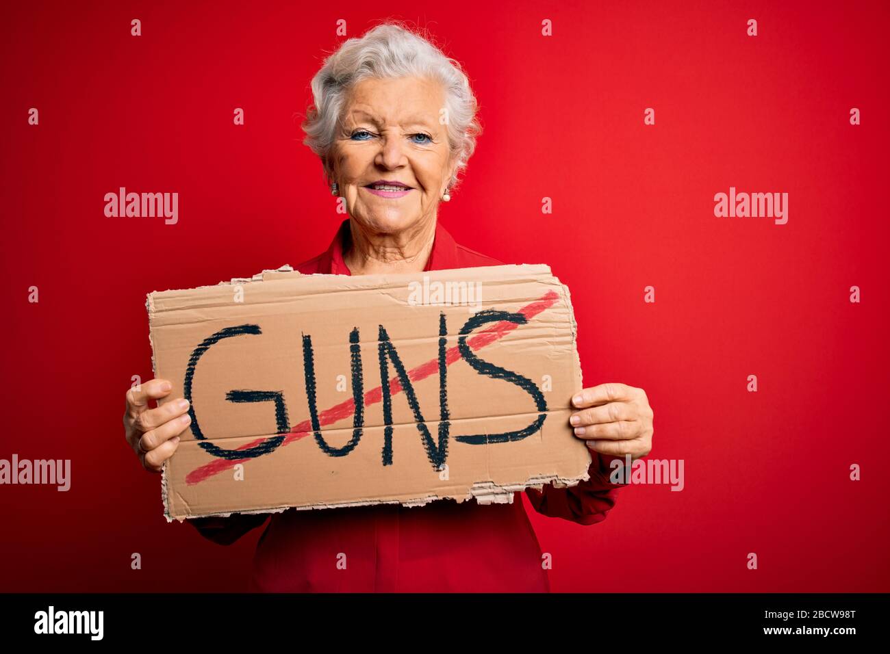 Senior beautiful grey-haired woman holding banner with prohibited guns ...