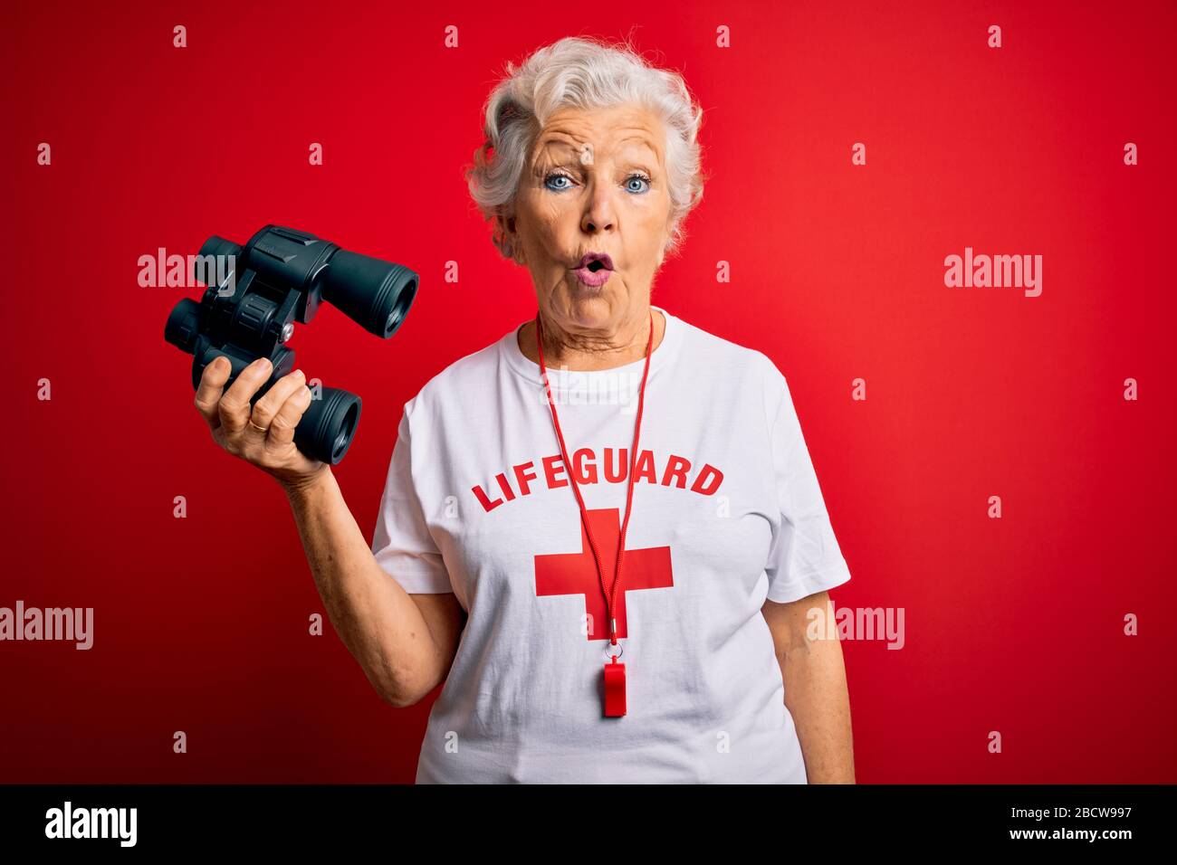 Senior beautiful grey-haired lifeguard woman using binoculars and ...