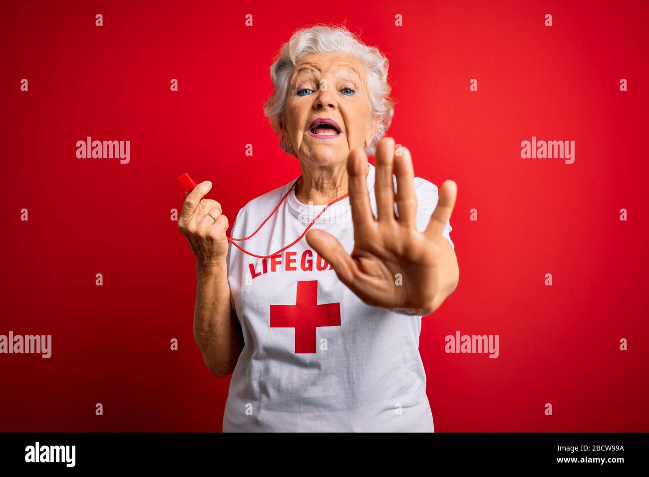 Senior beautiful grey-haired lifeguard woman wearing t-shirt with red ...