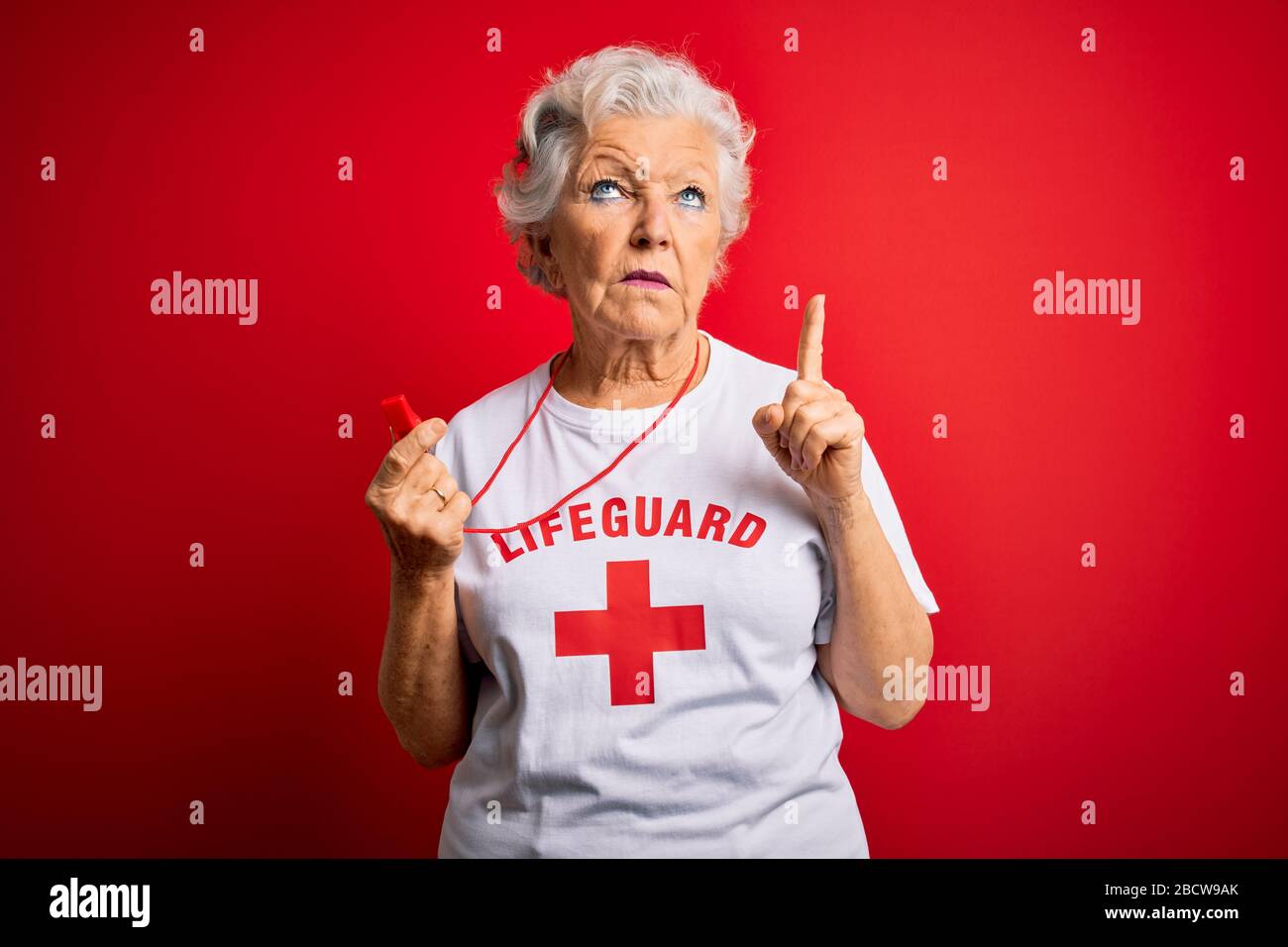 Senior beautiful grey-haired lifeguard woman wearing t-shirt with red ...