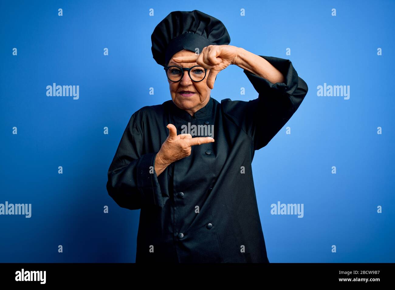 Senior beautiful grey-haired chef woman wearing cooker uniform and hat ...
