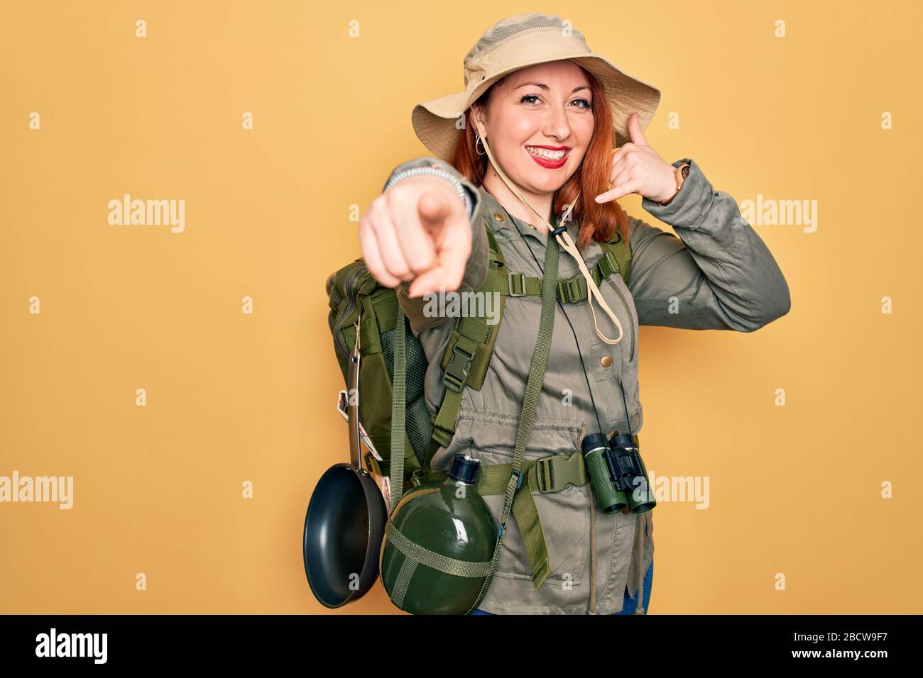 Young redhead backpacker woman hiking wearing backpack and hat over ...