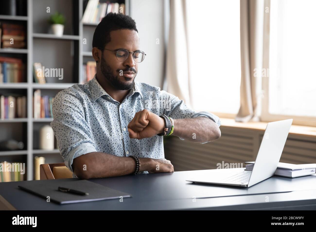 African American male employee check time at work Stock Photo - Alamy