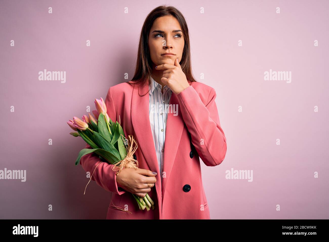 Young beautiful brunette woman holding bouquet of tulips flowers over ...