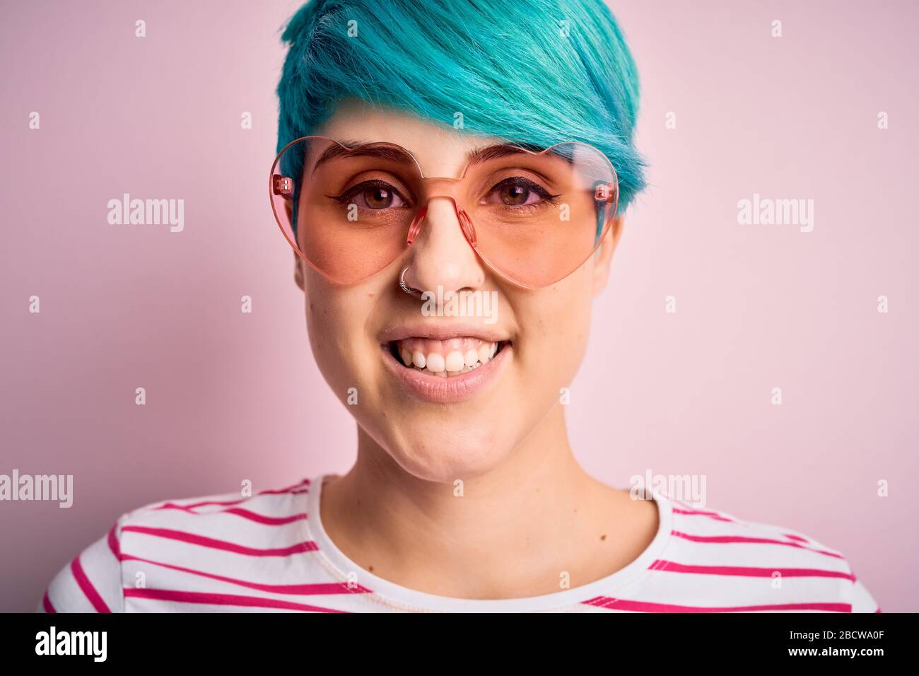 Young beautiful woman with blue fashion hair wearing fanny glasses with ...