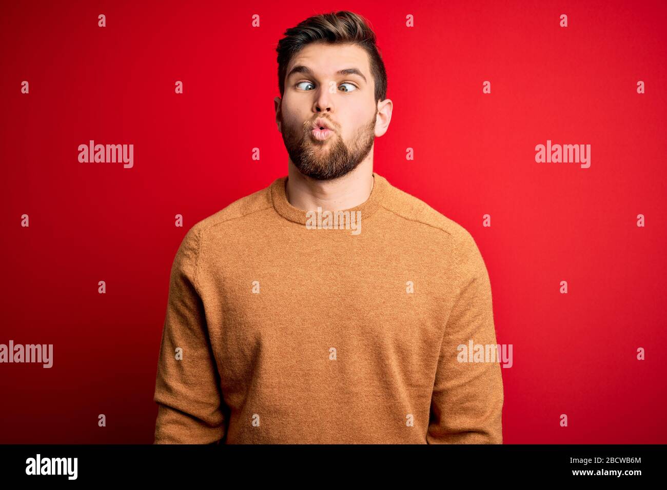 Young blond man with beard and blue eyes wearing casual sweater over ...