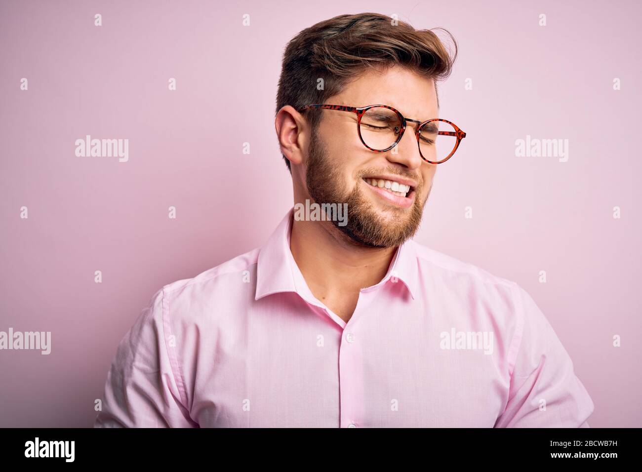 Young handsome blond man with beard and blue eyes wearing pink shirt ...