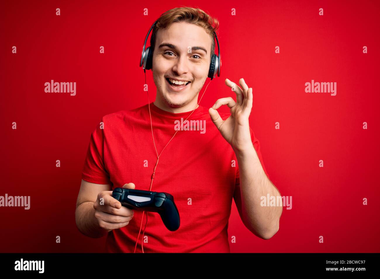 Young handsome redhead gamer man playing video game using headphones ...