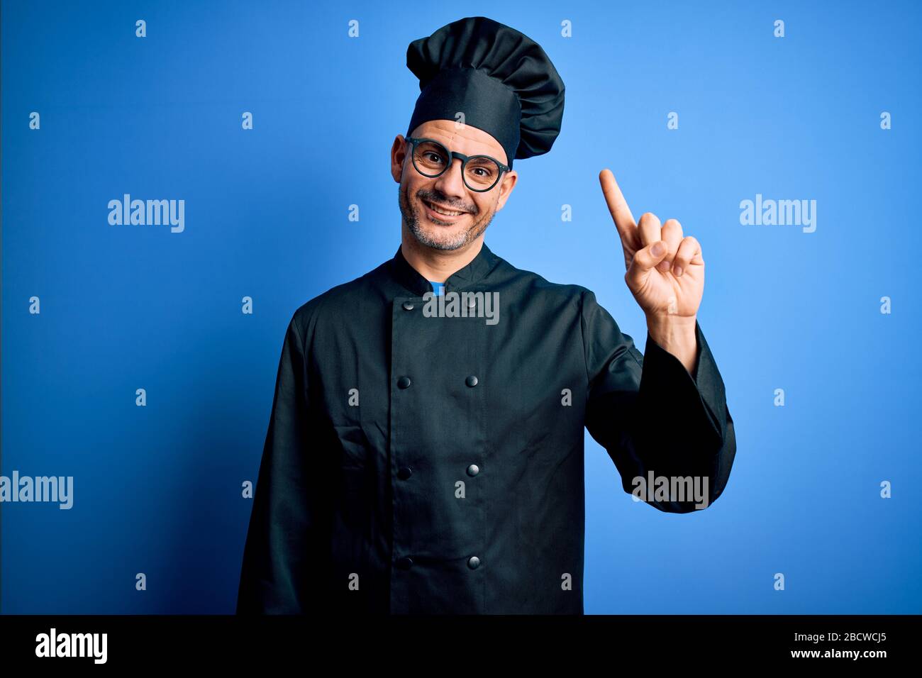 Young handsome chef man wearing cooker uniform and hat over isolated ...