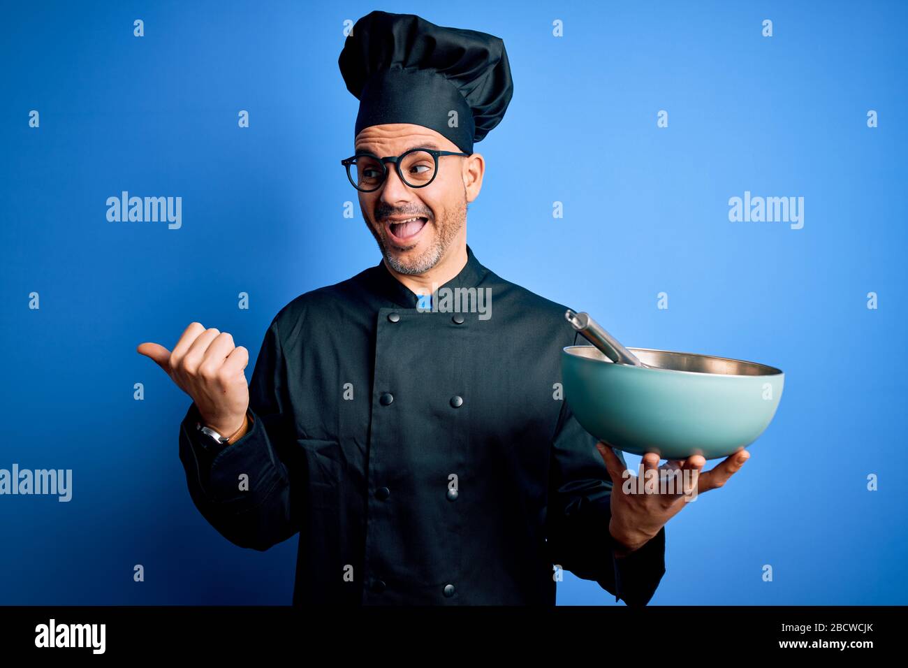 Young handsome chef man wearing cooker uniform and hat mixing using ...