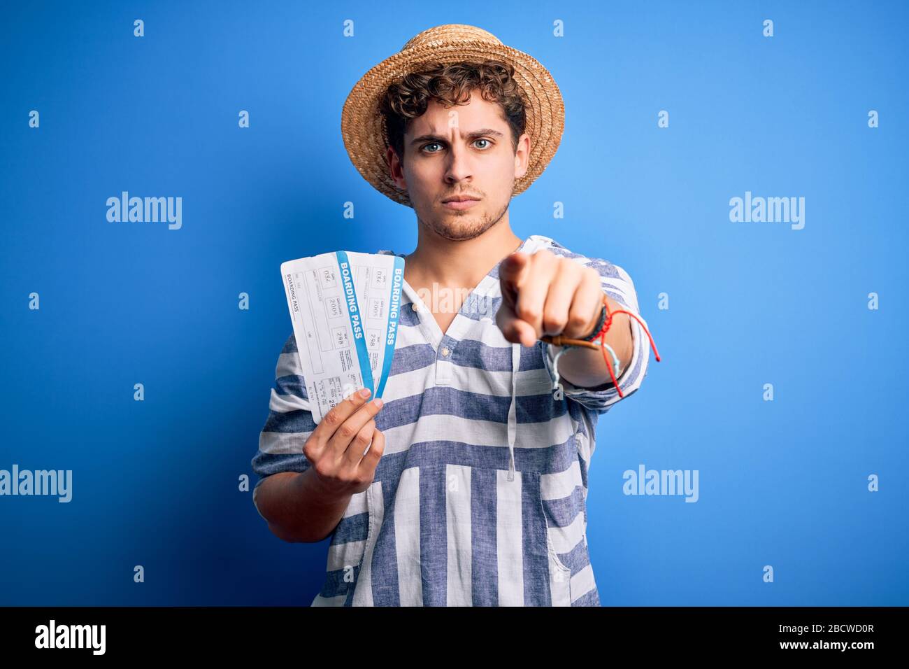 Young blond tourist man with curly hair on vacation wearing summer hat ...