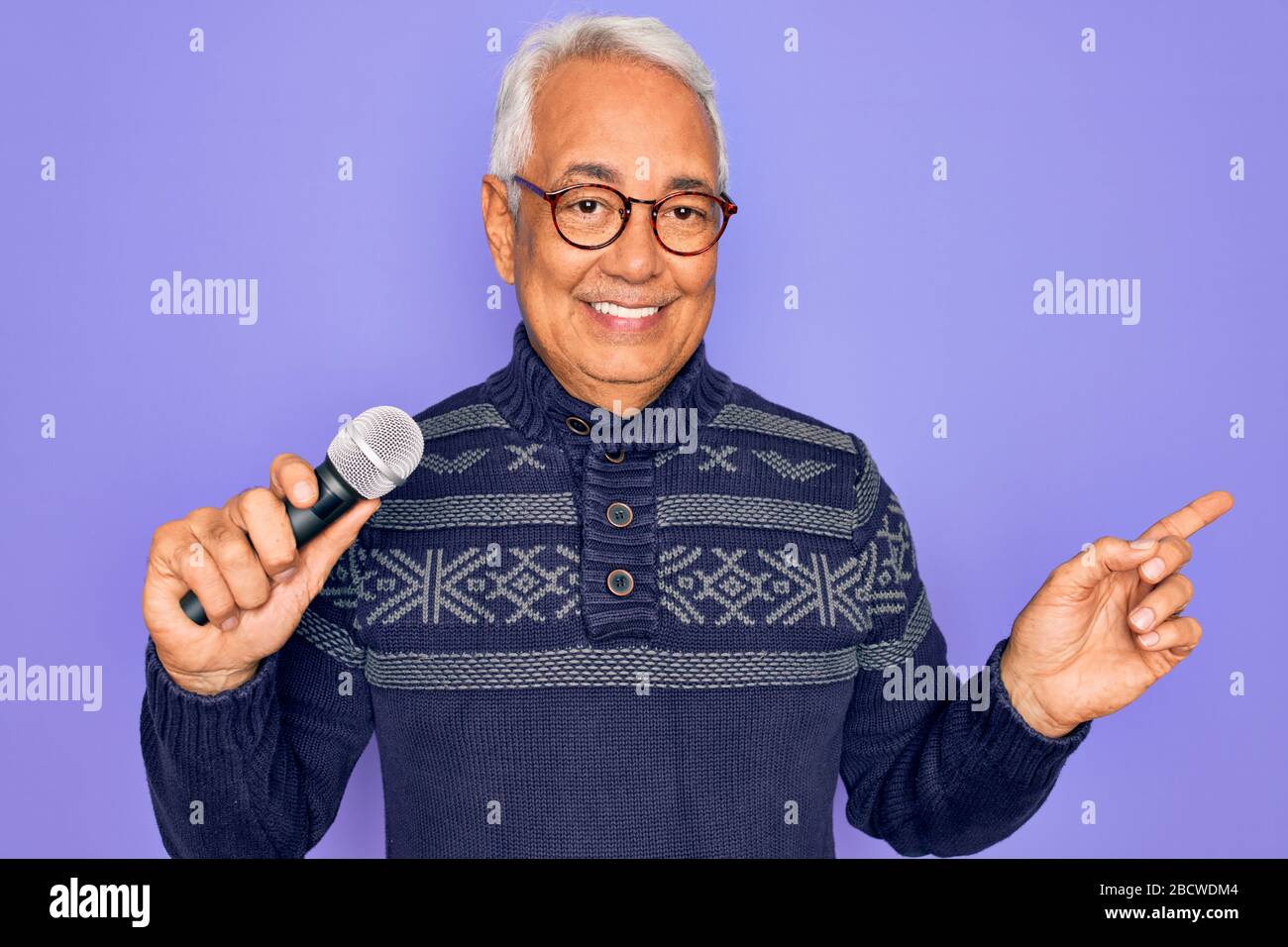 Middle age senior grey-haired singer man singing using music microphone ...