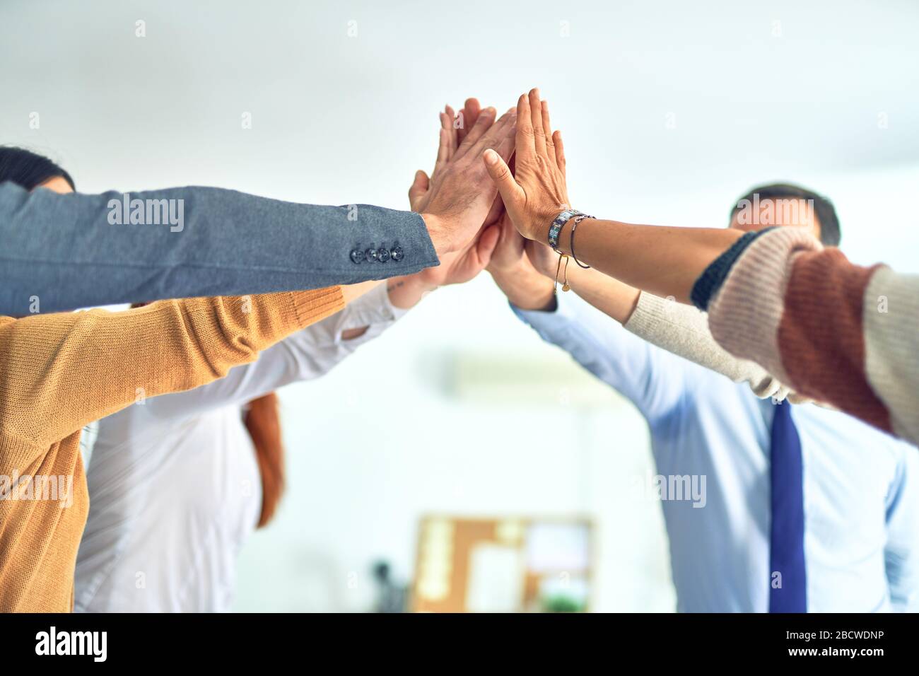 Group of business workers standing with hands together highing five at ...