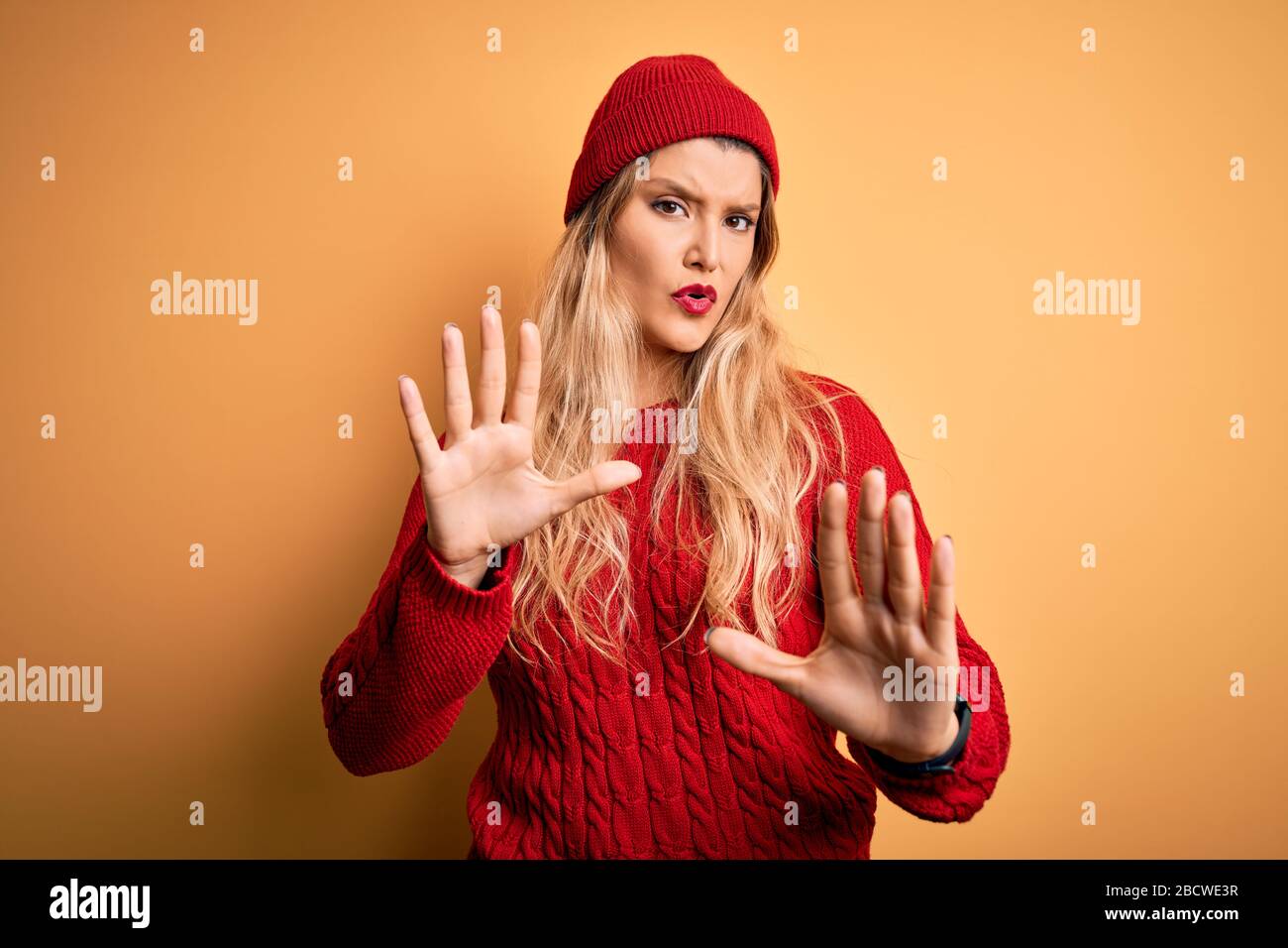 Young beautiful blonde woman wearing casual sweater and wool cap over ...
