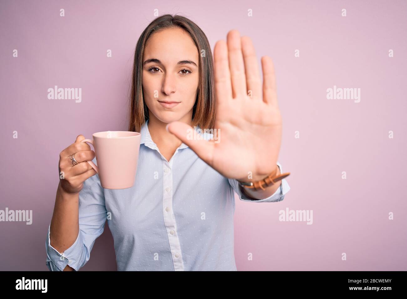 Young beautiful woman drinking mug of coffee standing over isolated ...