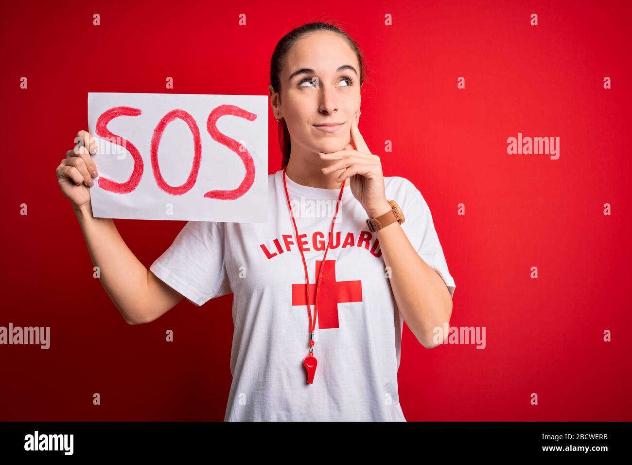 Lifeguard woman wearing t-shirt with red cross and whistle holding ...