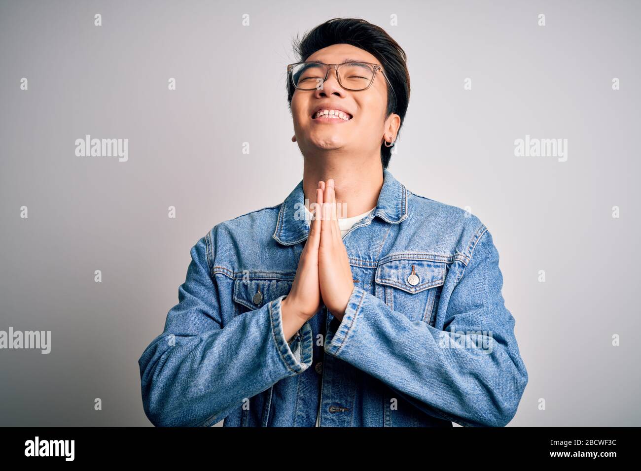 Young handsome chinese man wearing denim jacket and glasses over white ...