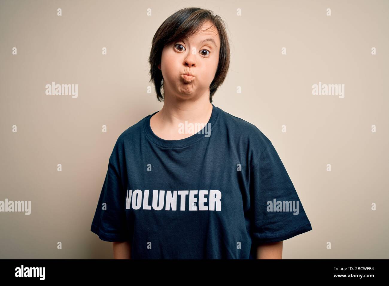 Young down syndrome volunteer woman wearing social care charity t-shirt ...