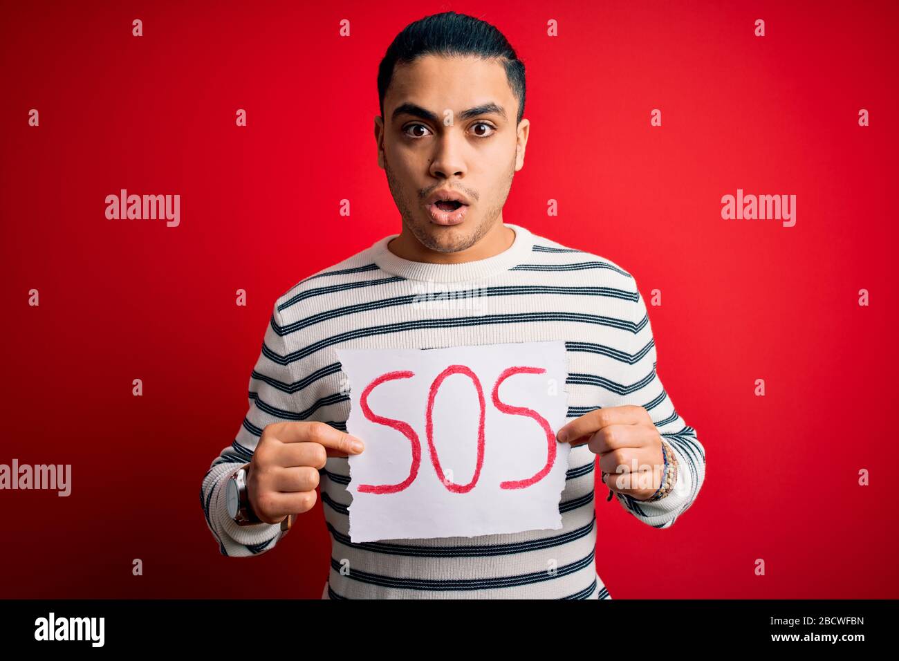Young brazilian man with problem holding banner with sos message over ...