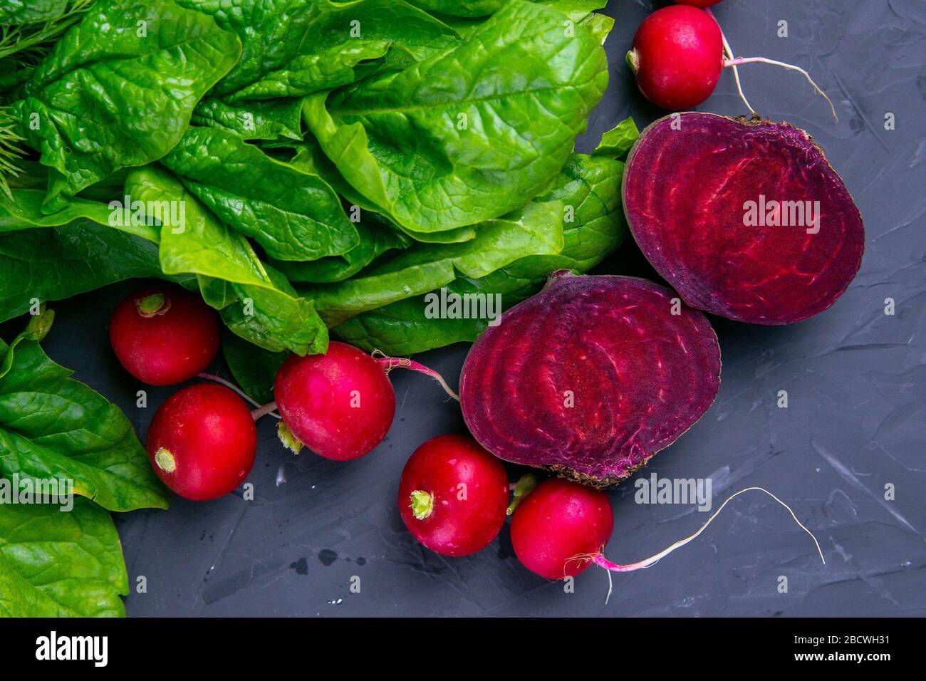 Fresh vegetables and greens radish, spinach, beet on a black background ...