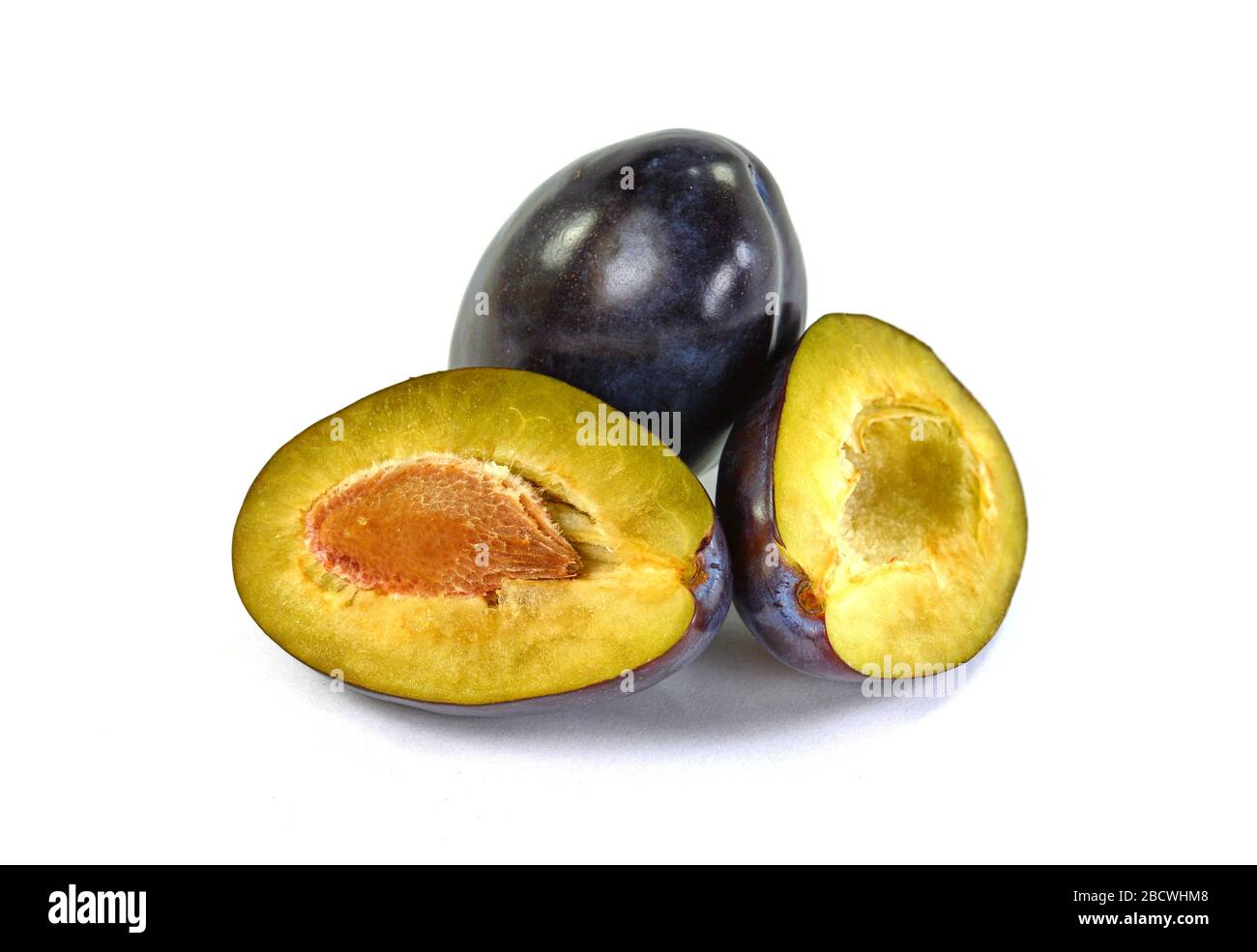 Plums cut in half isolated on white background Stock Photo - Alamy