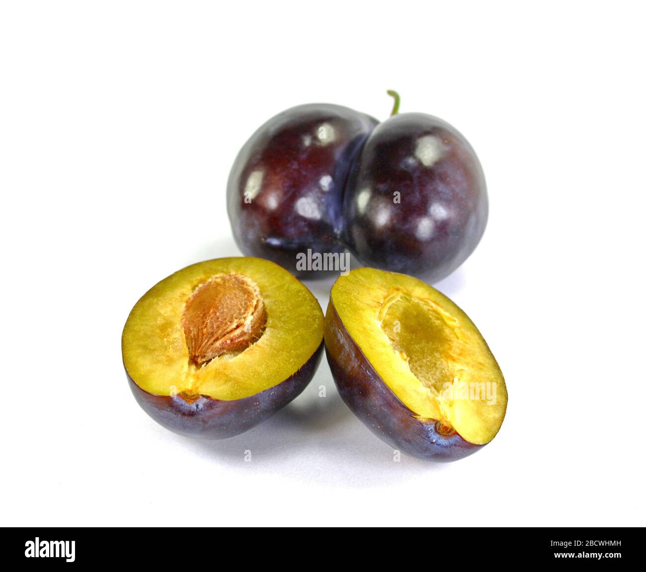 Plums cut in half isolated on white background Stock Photo - Alamy