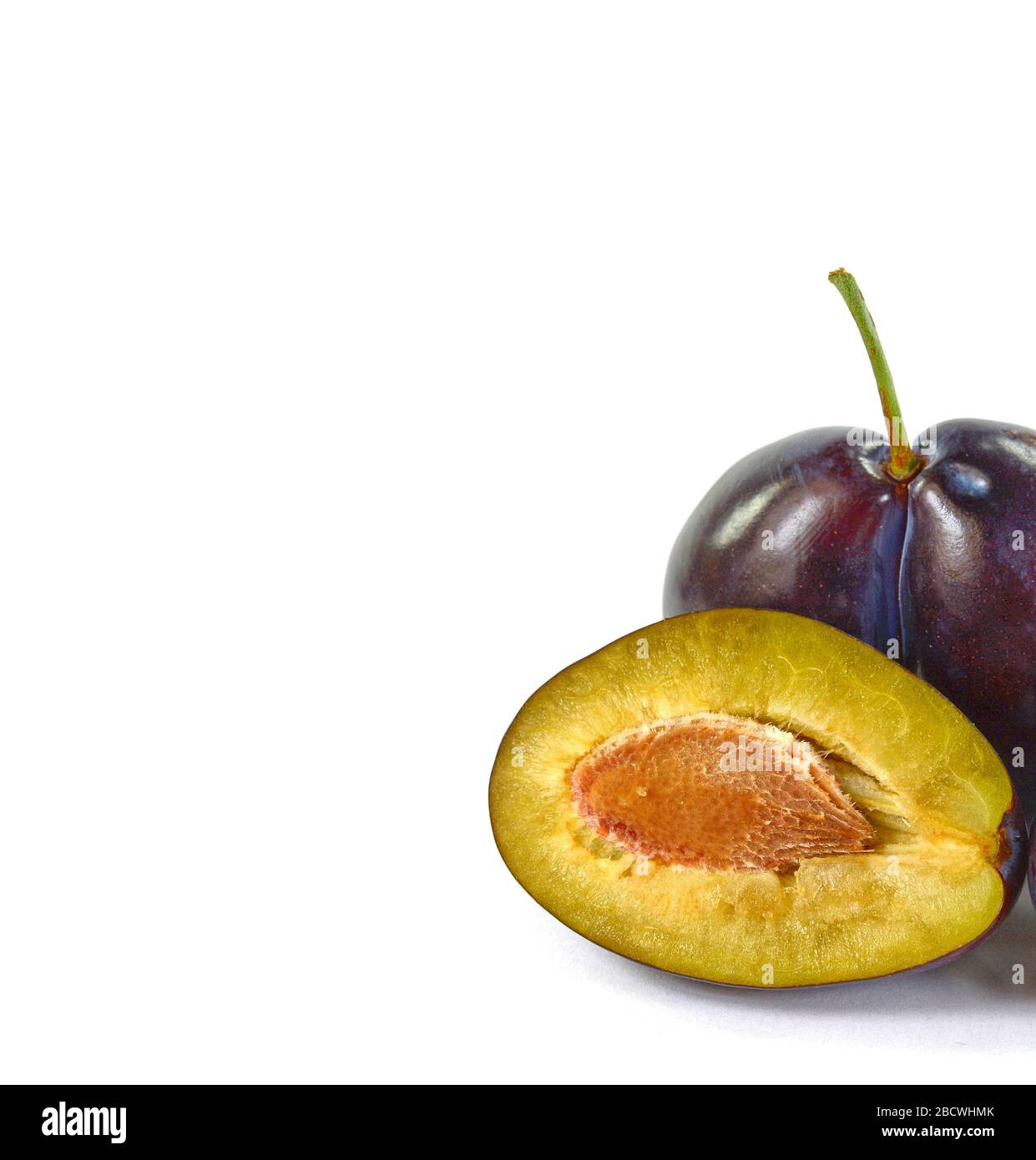 Plums cut in half isolated on white background Stock Photo - Alamy