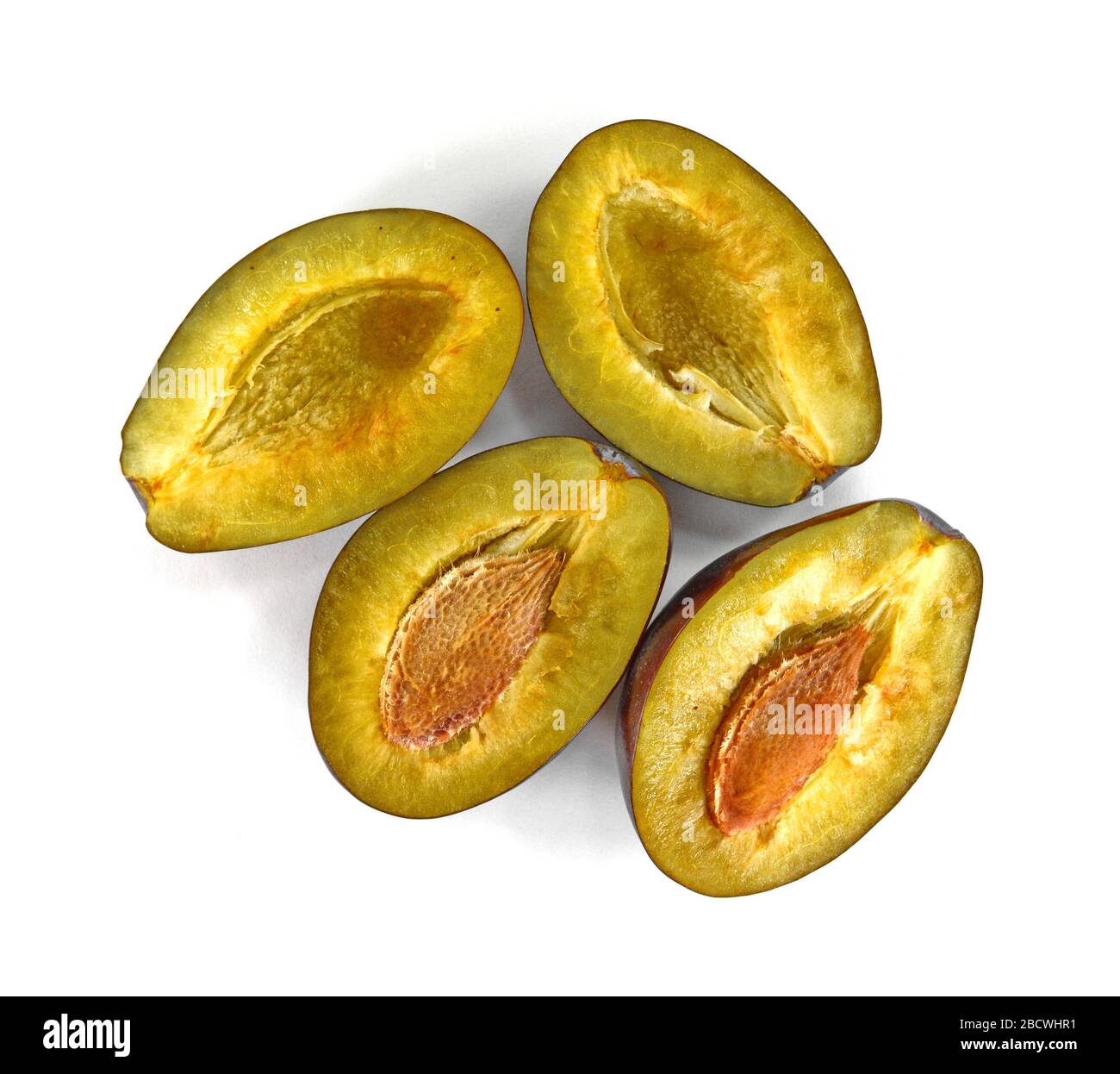 Plums cut in half isolated on white background Stock Photo - Alamy