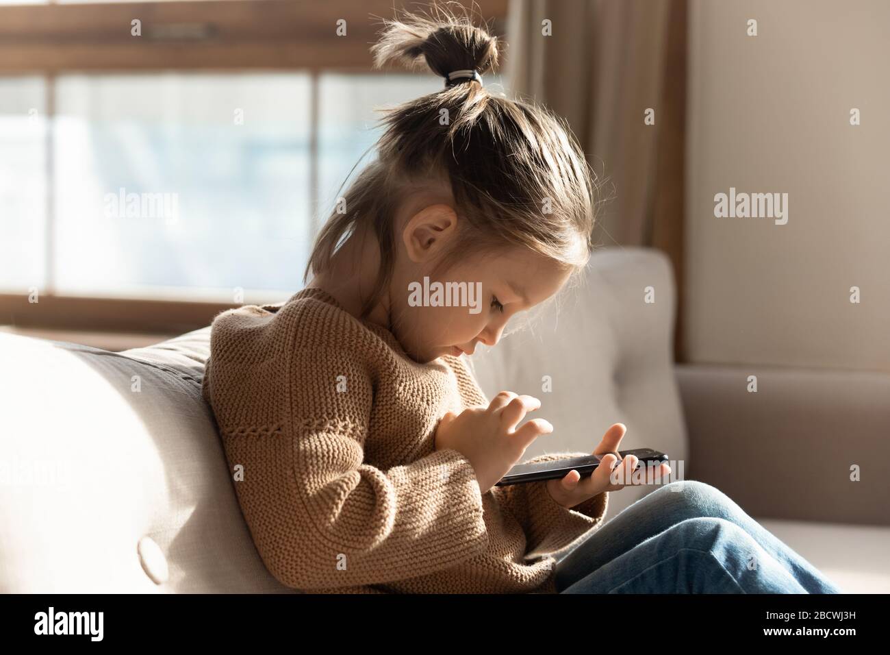Little preschool girl using smartphone application alone Stock Photo ...