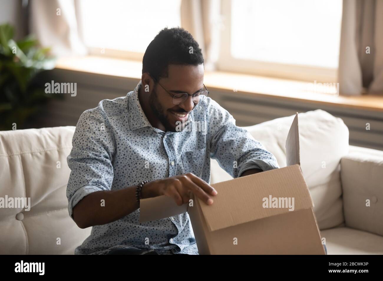 Excited biracial man unpack internet delivery order package Stock Photo ...