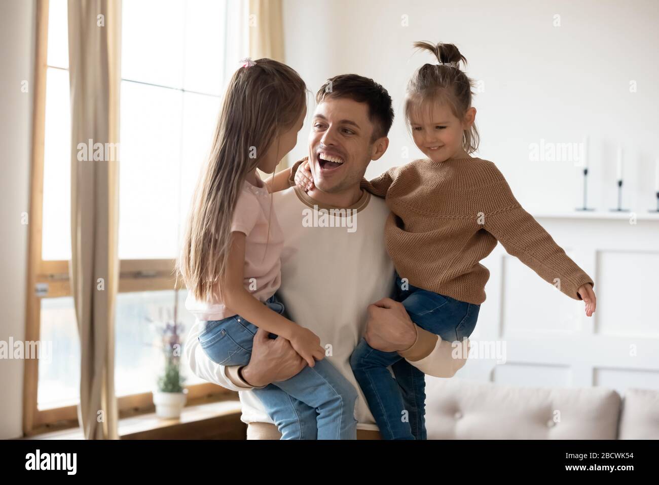Overjoyed young father holding two little children siblings Stock Photo ...