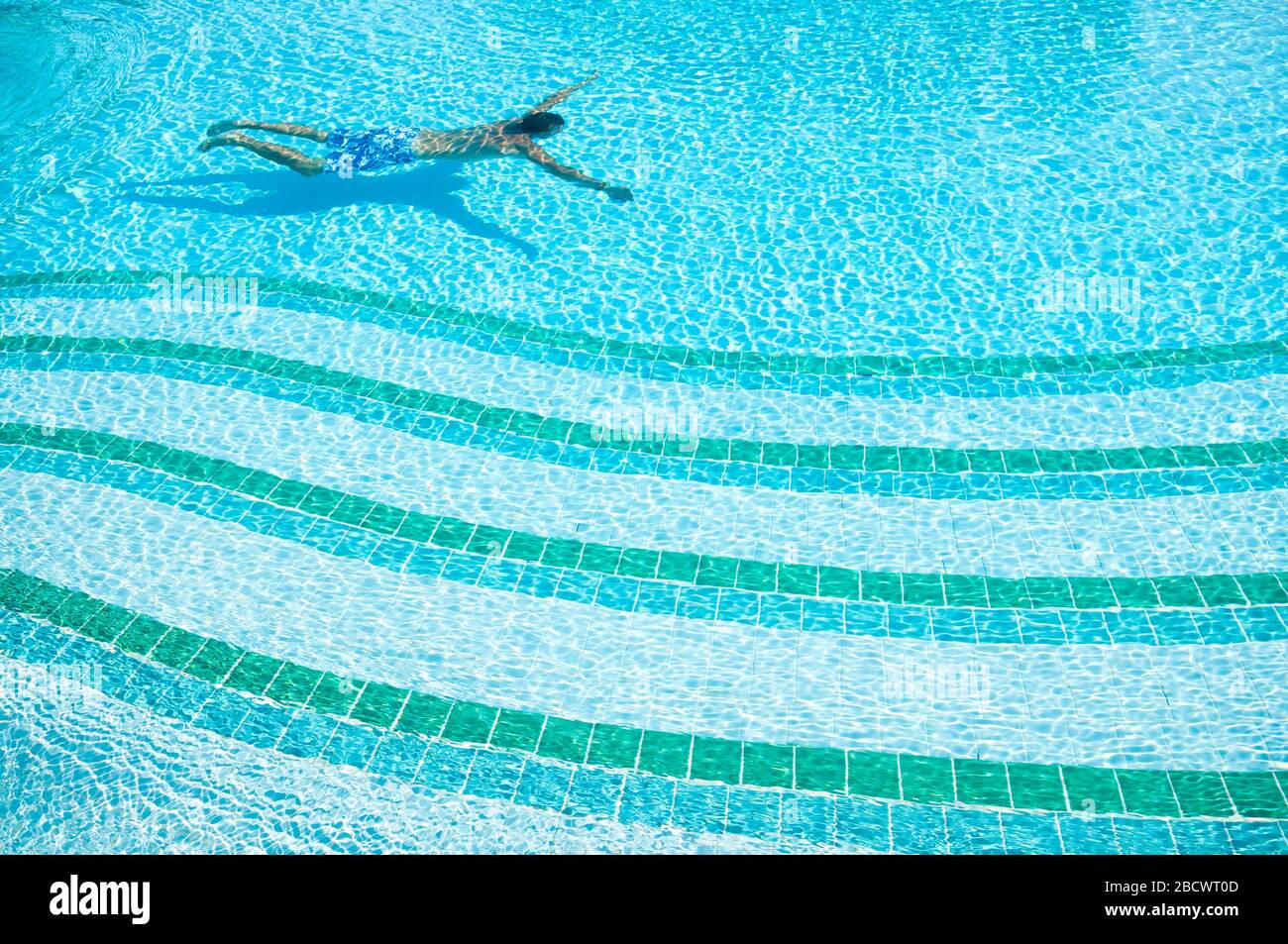 Unrecognizable man swimming underwater in a bright blue pool Stock ...