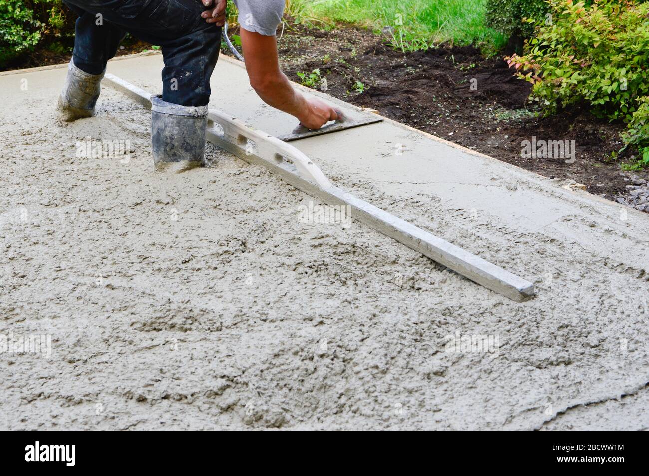 Man leveling cement with a long wooden level and a trowel Stock Photo ...