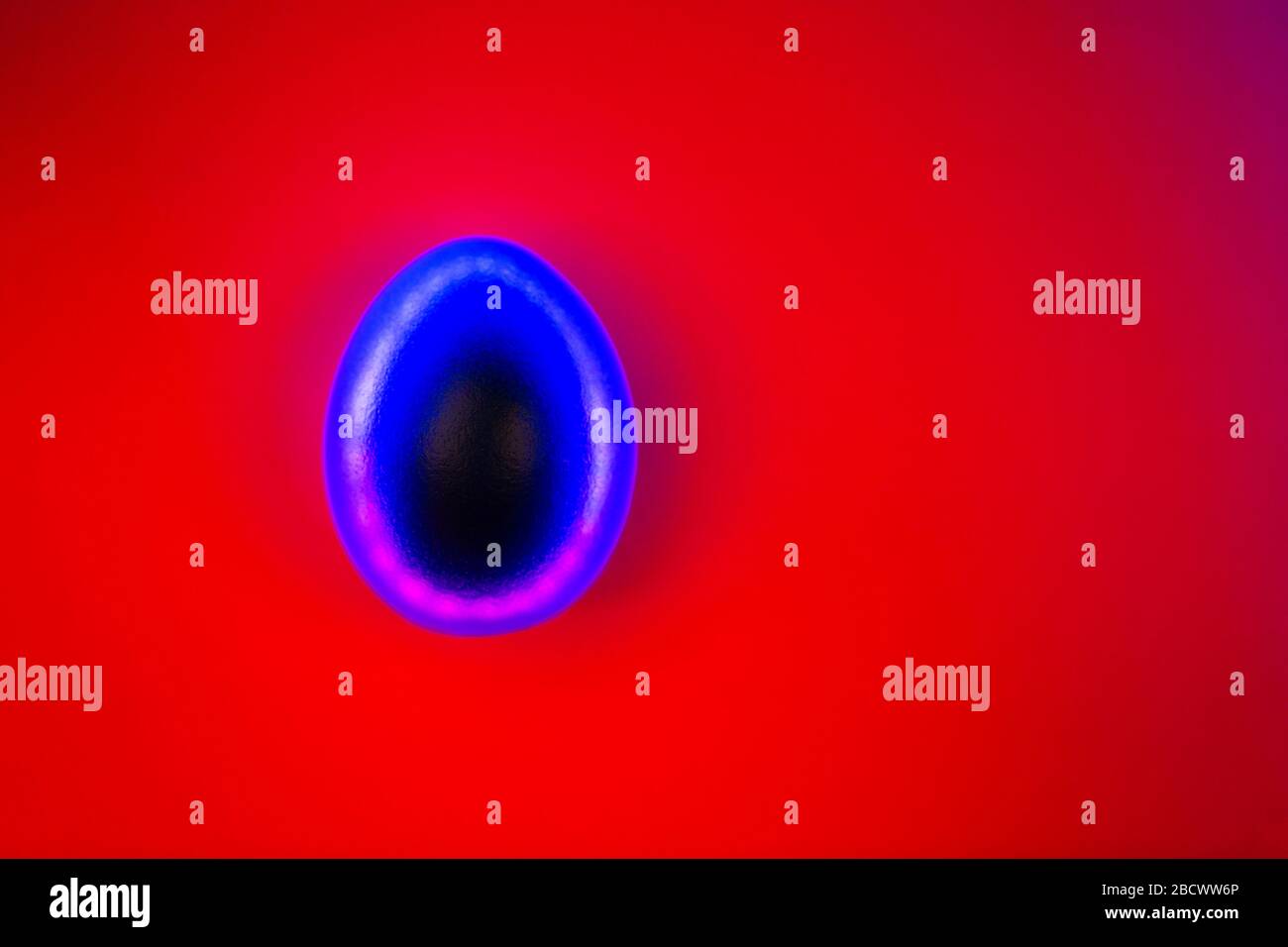 Glossy blue egg with creative neon backlight on bright red background ...