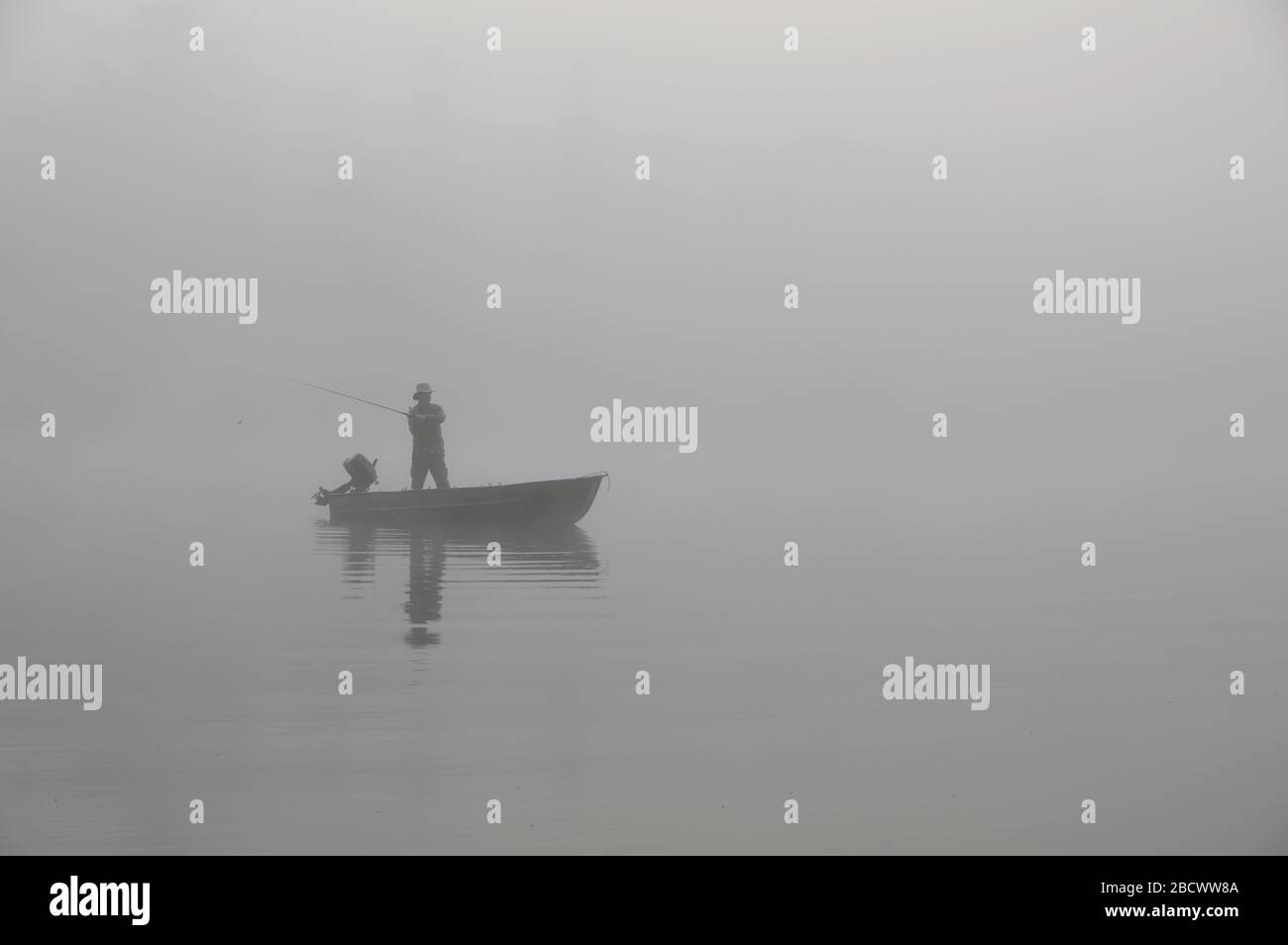 Picture of a fisherman fishing from a row boat in the fog Stock Photo ...