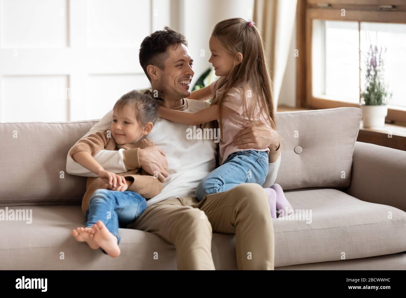 Smiling young father playing with small cute kids daughters Stock Photo ...