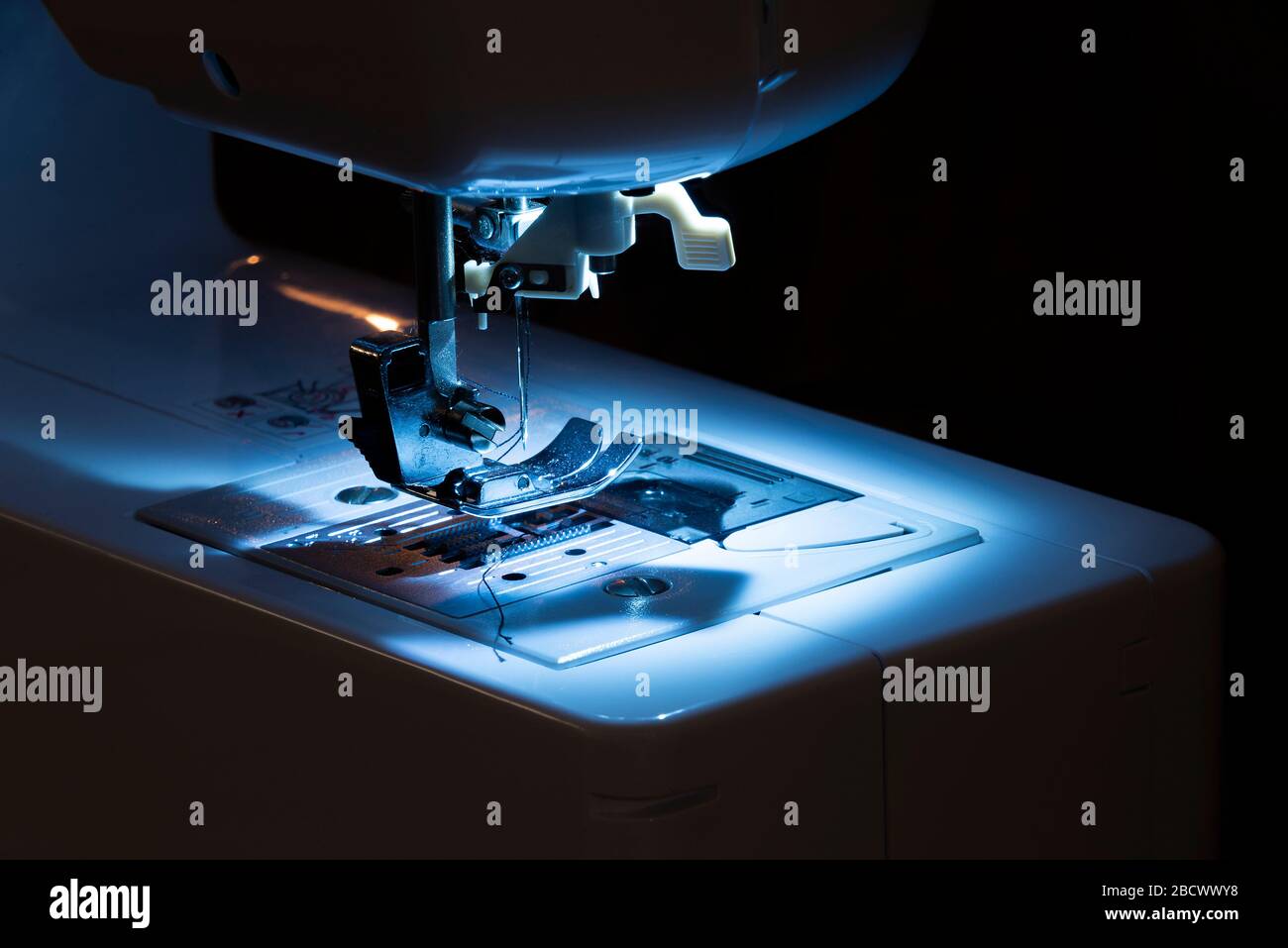Covid 19 activities. Close up of a sewing machine at night, illuminated ...