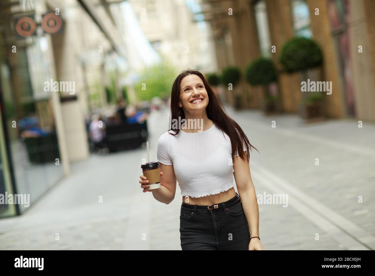 a young woman walking with a drink Stock Photo - Alamy
