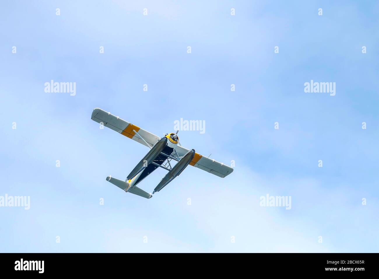 Float plane flying with a partly blue sky background surrounding it, in ...