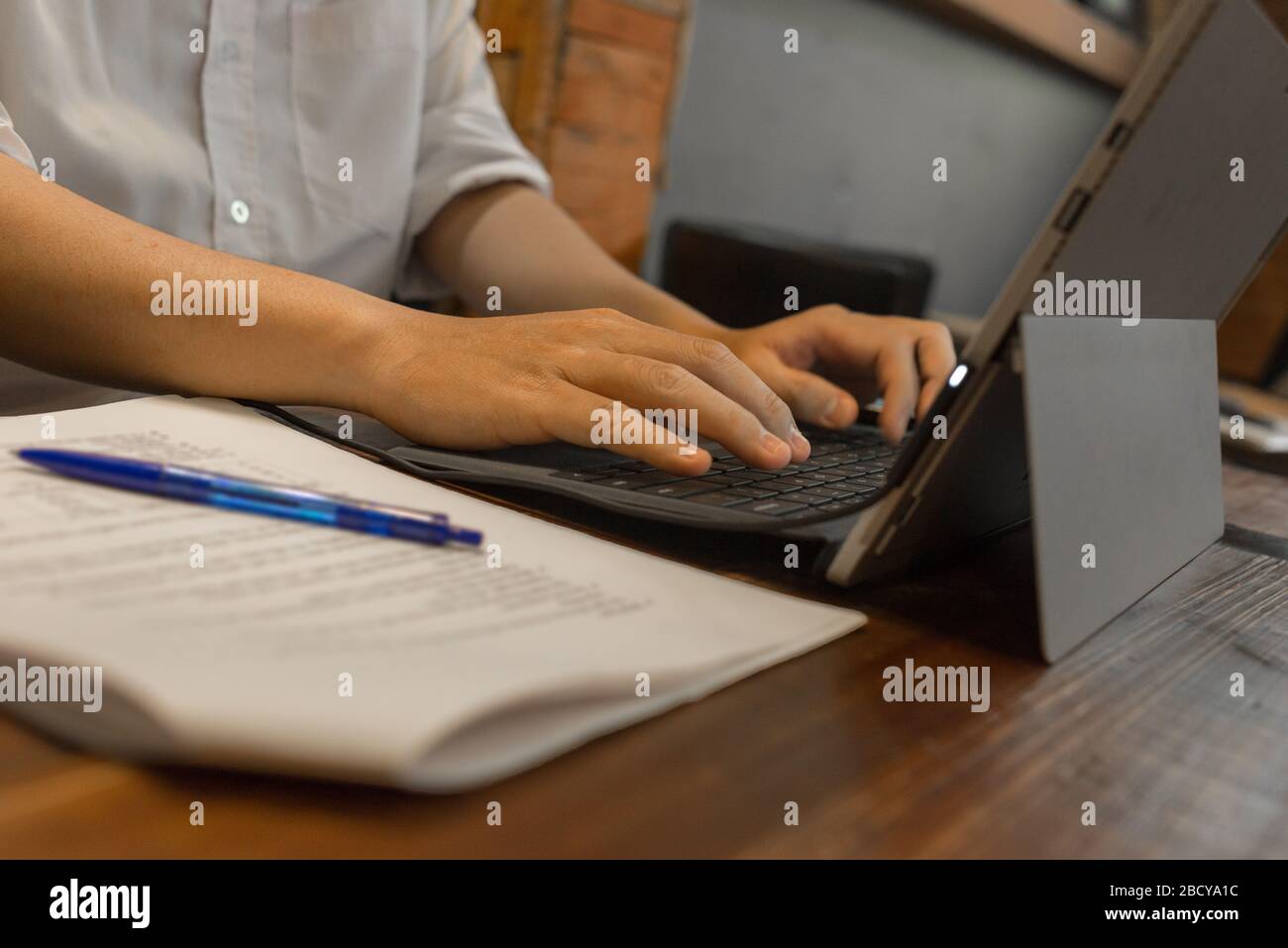 Human hands typing laptop keyboard on wooden table Stock Photo - Alamy