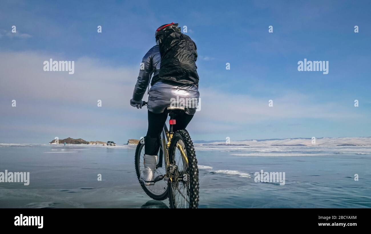 Woman is riding bicycle on the ice. Tires on bike are covered wi Stock ...