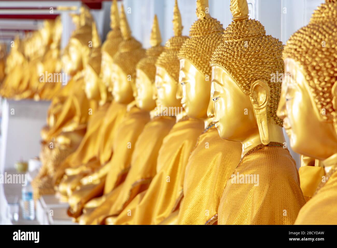 A long line of golden statues of the Buddha at Buddhist temple in ...