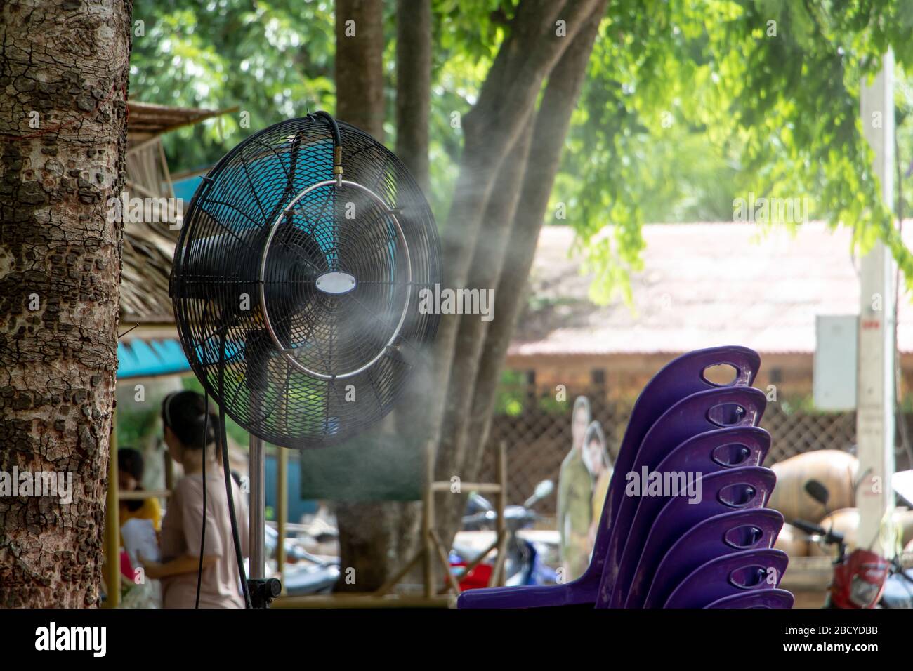Rotating fan spraying water to the surrounding. Outdoor fan in tropical ...