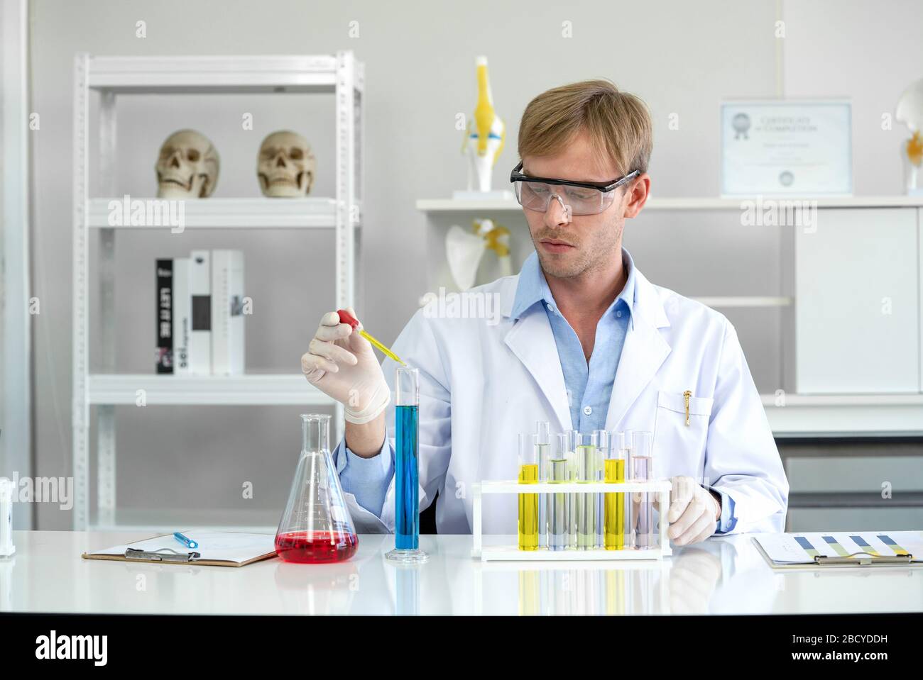 A young Brazilian scientist with a safety glasses lab is mixing ...